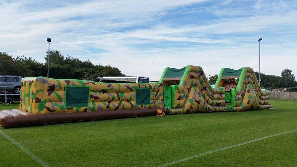 75ft inflatable army assault course in a field - Monster Event Hire